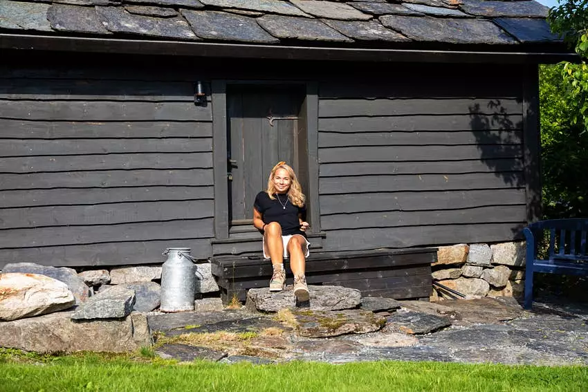 Žena sediaca pred tradičnou nórskou stodolou