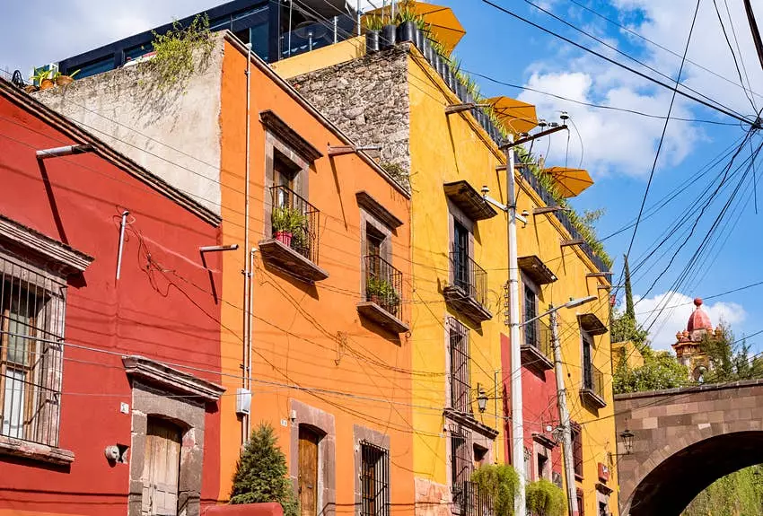 Červené, žlté a oranžové budovy pod modrou oblohou v mexickom meste San Miguel de Allende