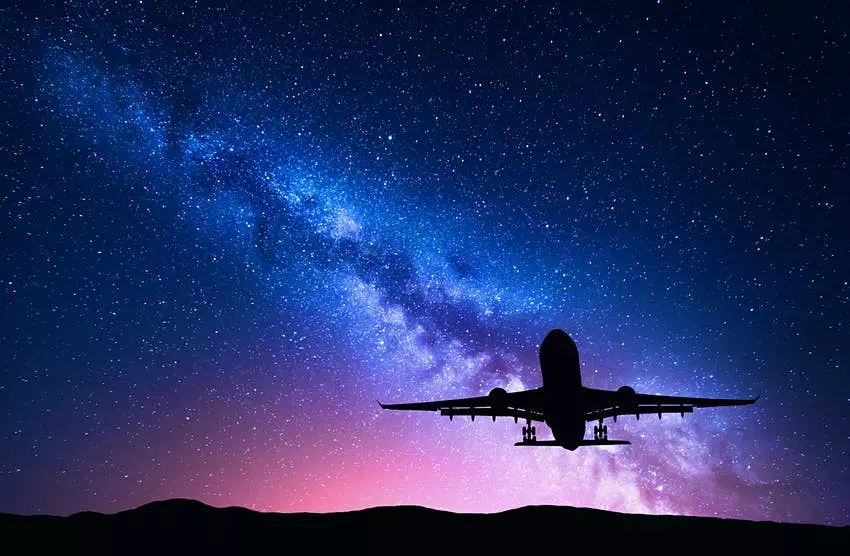 Mliečna dráha a silueta lietadla. Krajina s osobným lietadlom letí v noci na hviezdnej oblohe. Priestor pozadia. Pristávacie lietadlo na pozadí farebnej Mliečnej dráhy. Lietadlá