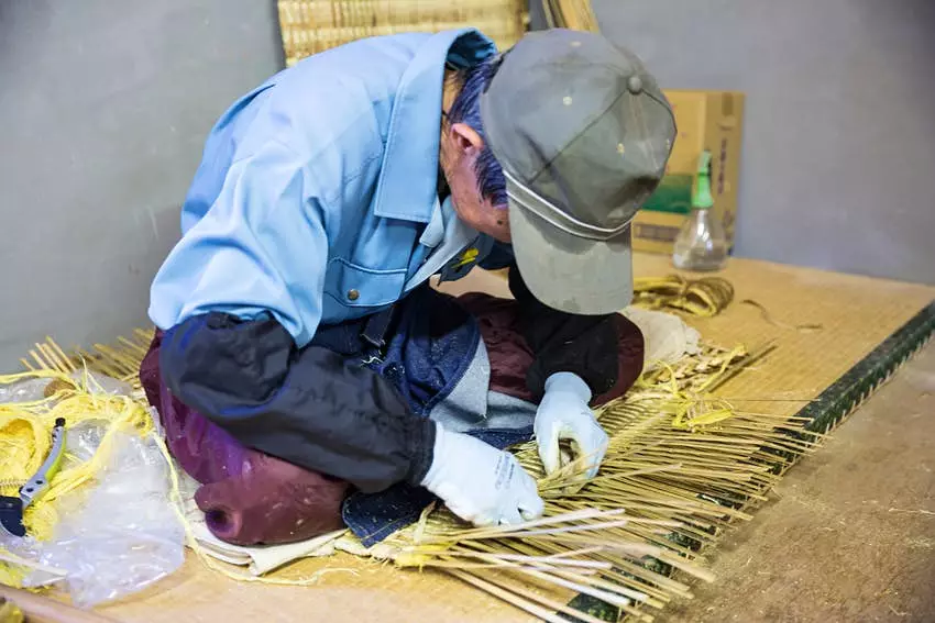 Sediaci remeselník ohýba nízke a pletie bambusové koše, čo je tradičná technika, ktorej hrozí vyhynutie